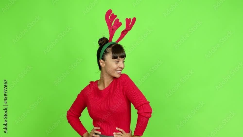 Young Woman Wearing Christmas Hat Posing With Arms At Hip And Laughing