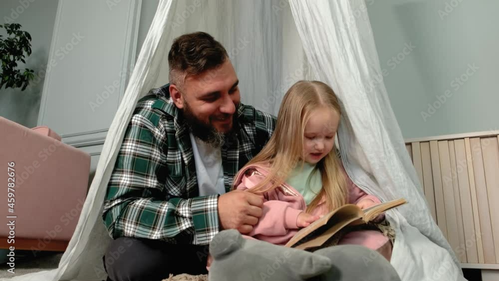 Happy parent male and small daughter having fun reading book sitting in ...
