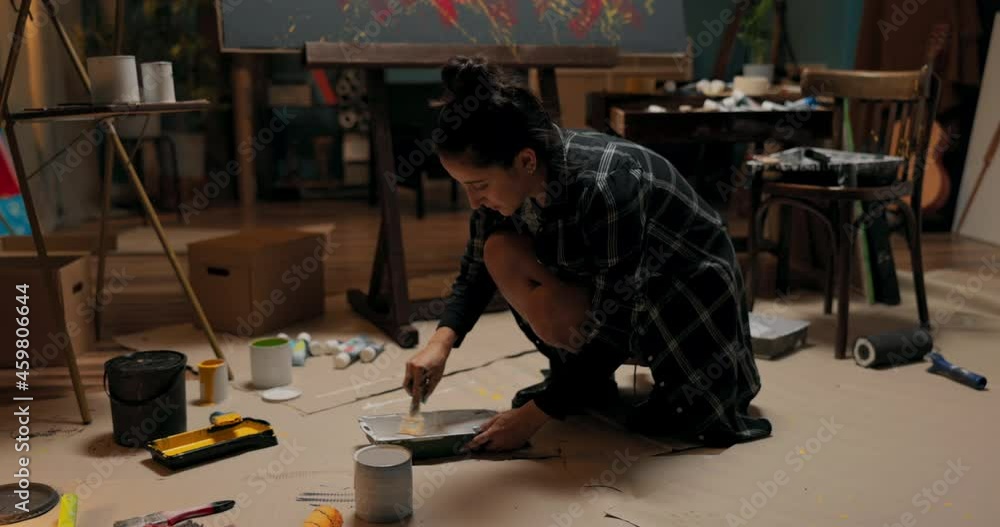 A talented woman is crouch,working in her studio, school, and art class ...