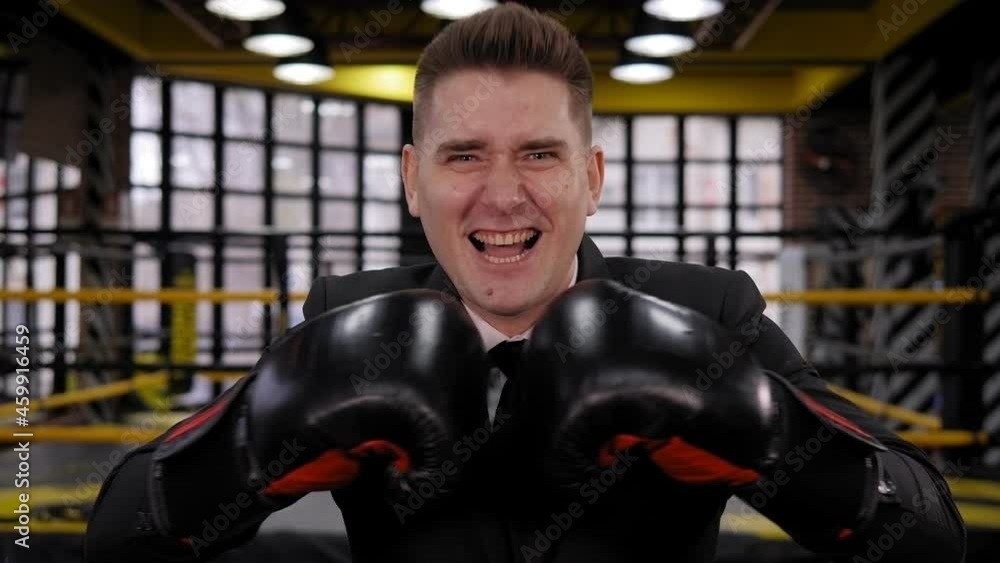 Portrait of an angry aggressive businessman in a black suit and boxing ...