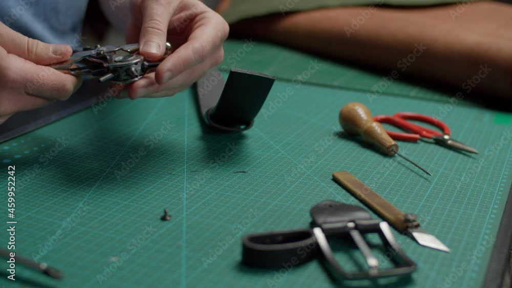 Close-up of workman hands taking puncher on work table, making hole in ...