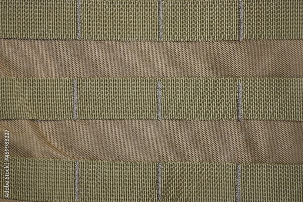 green texture of fabric from a part of a backpack with sewn stripes ...
