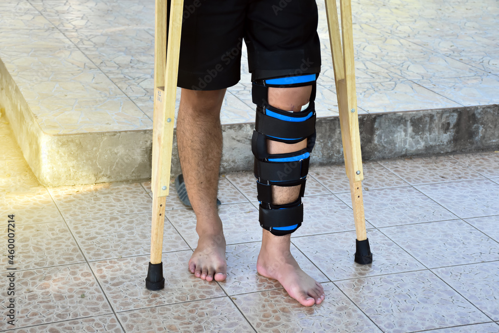 A man who has a left broken leg which wrapped with knee pad walks on ...
