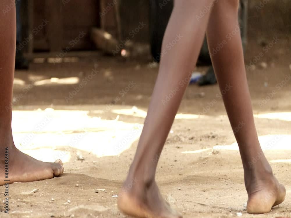 African girls play rubber band jumping. Close up of their bare feet ...