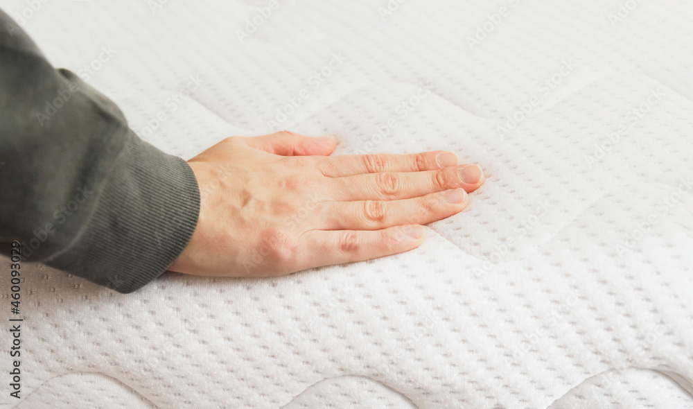 Hand touching and pressing orthopedic mattress on bed. Stock Photo ...