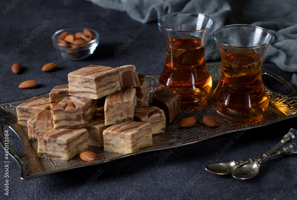 Tea ceremony with Uzbek sweet milk halva with almonds and cocoa on dark ...