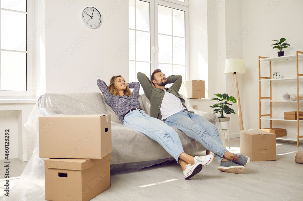 Happy married couple taking break while moving in new home. Tired ...