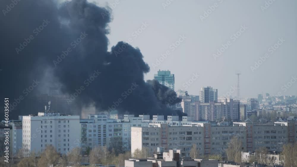 Black smoke rises and swirls over the rooftops of high-rise buildings ...
