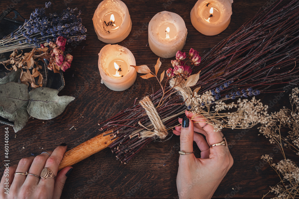 Wiccan witch decorating a DIY besom broom for Samhain celebration. Hand ...