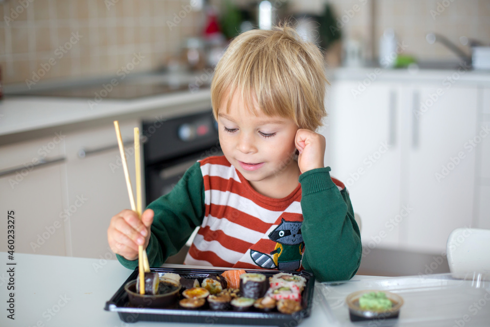 Cute blond child Eat Sushi Rolls At Home. Happy boy ready for eating ...