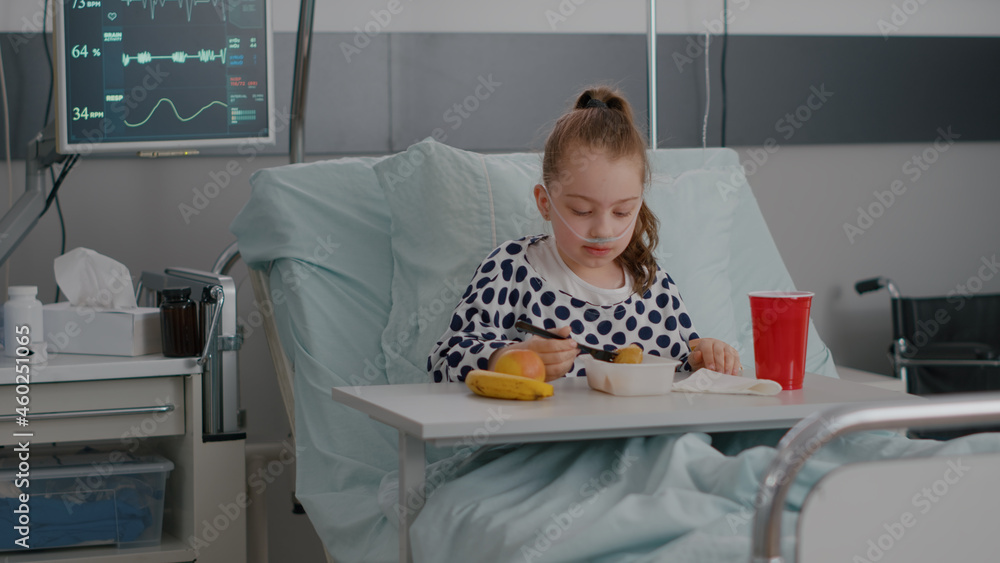 Portrait of hospitalized little child resting in bed eating healthy ...