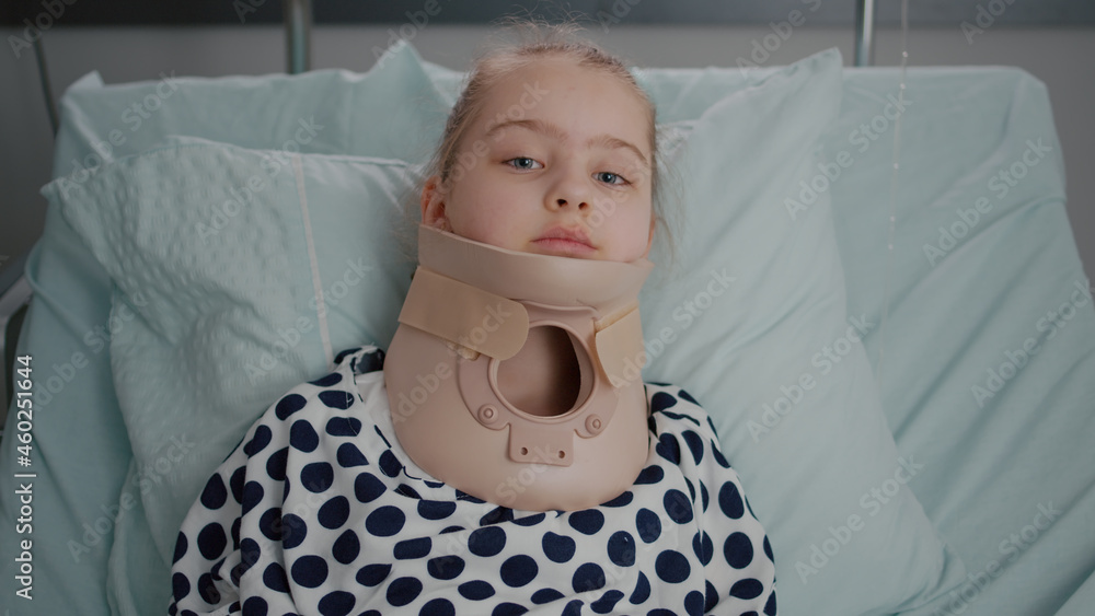 Portrait of sick little patient resting in bed looking at camera while ...