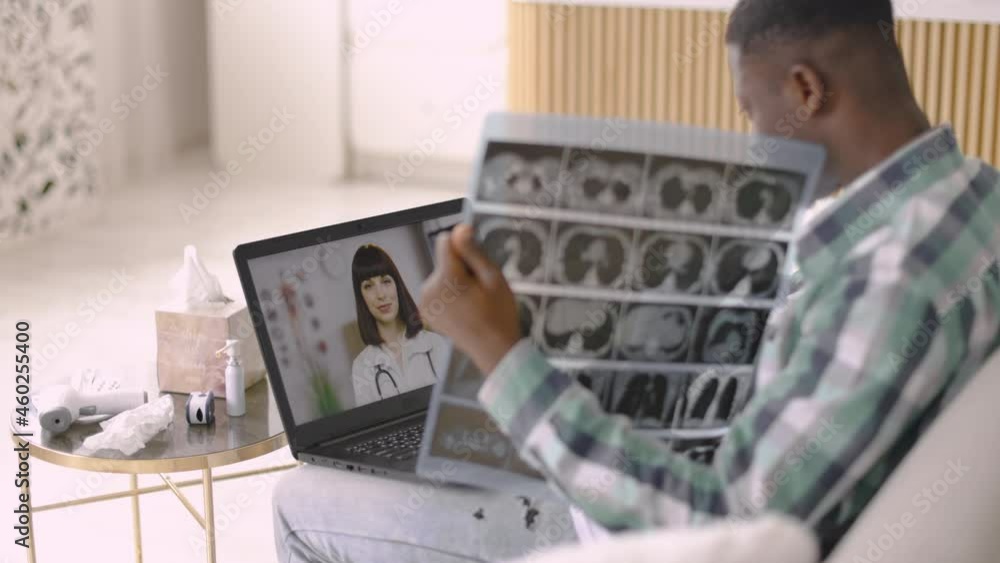 Remote medical appointment concept. Sick African man, sitting on sofa ...