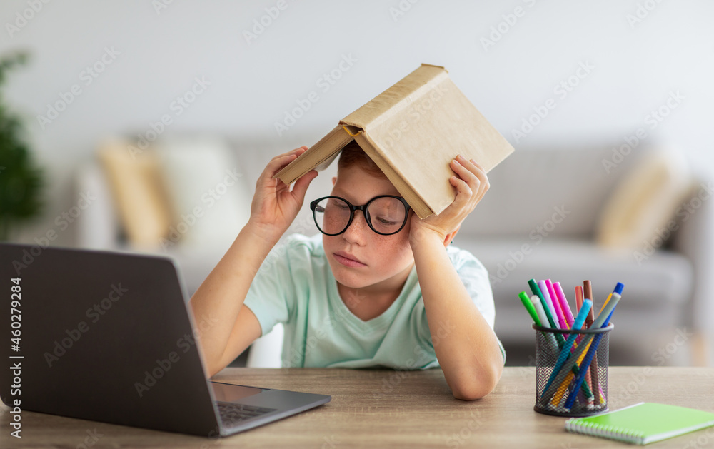 Bored boy doing homework in front of laptop at home Stock Photo | Adobe ...
