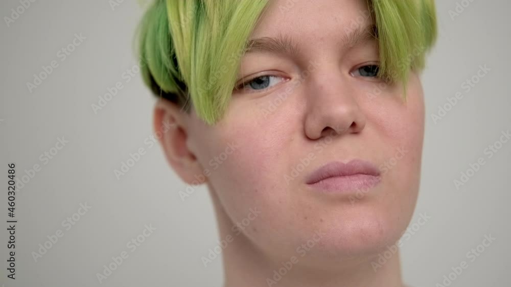 A young girl with a short pixie haircut and green hair in a white T ...