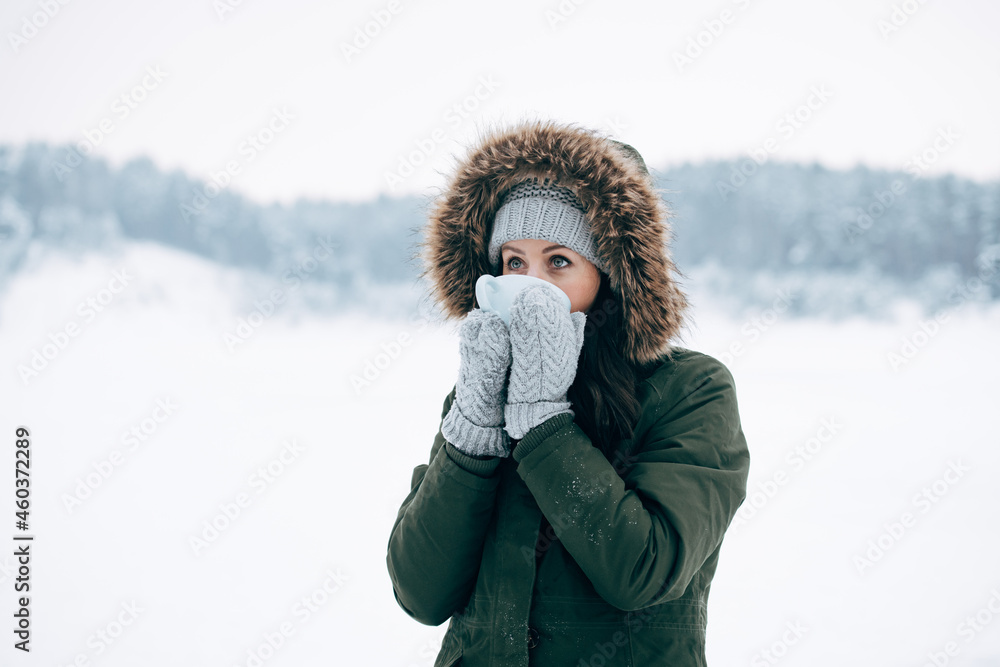 Beautiful young female smiling and drinking tea in nature Winter ...