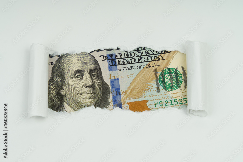 An image of a 100 dollar bill is visible in the torn hole of a sheet of ...