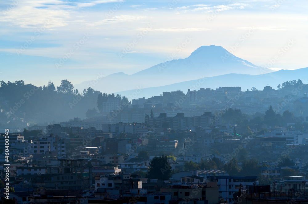 Quito in blue morning haze with fog and Cayambe volcano in background ...