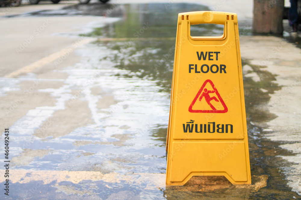 Yellow signs warning of Wet Floor and Caution to Slip are placed on wet ...