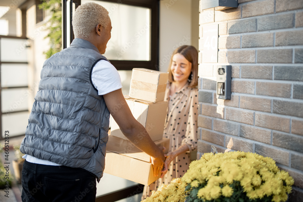 Delivery man giving parcels to caucasian woman on entrance of her house ...