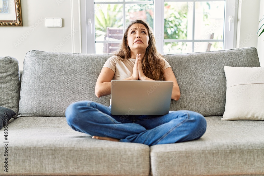 Beautiful young brunette woman sitting on the sofa using computer ...
