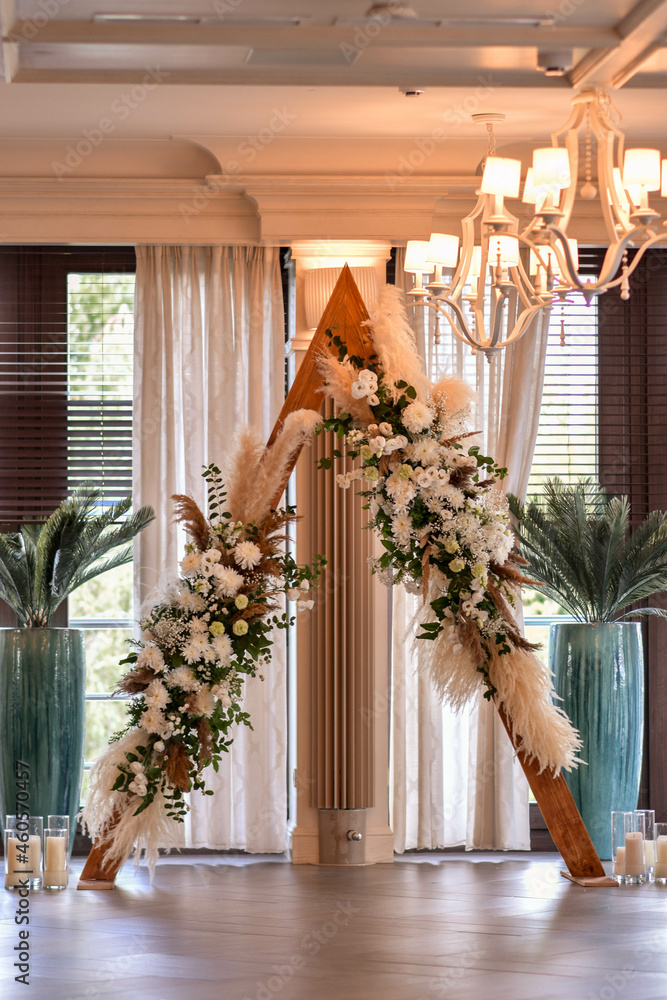Triangular wooden arch with composition of pampasian grass, dianthus ...