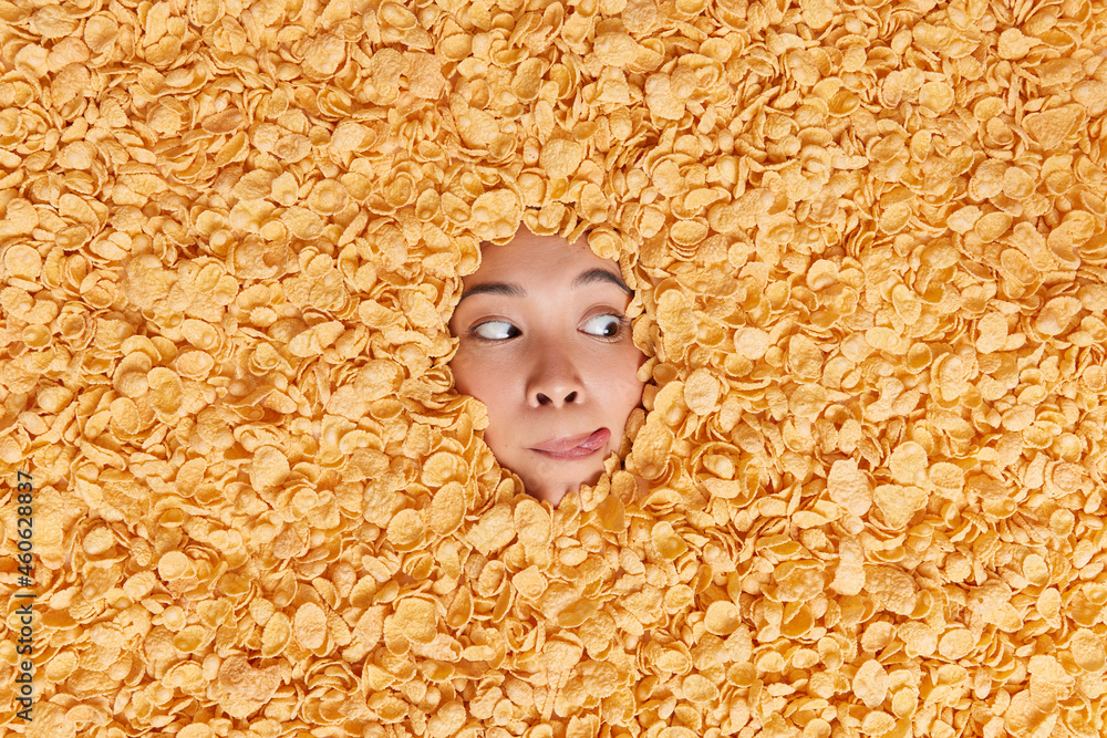 Funny woman foolishes around sticks out tongue makes grimace lies in ...