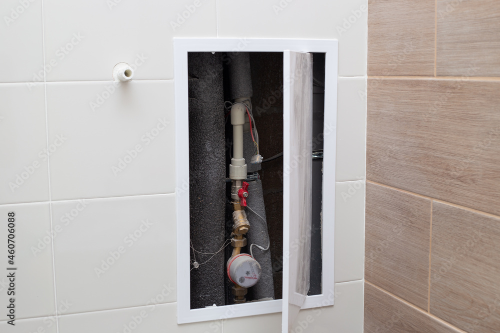 Foto de Bathroom wall hatch with pipes and water meter. Transmission of ...