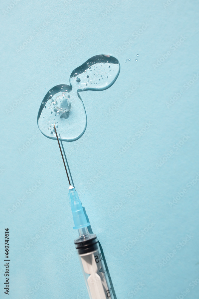 Disposable syringe with a transparent gel-like liquid on a blue ...