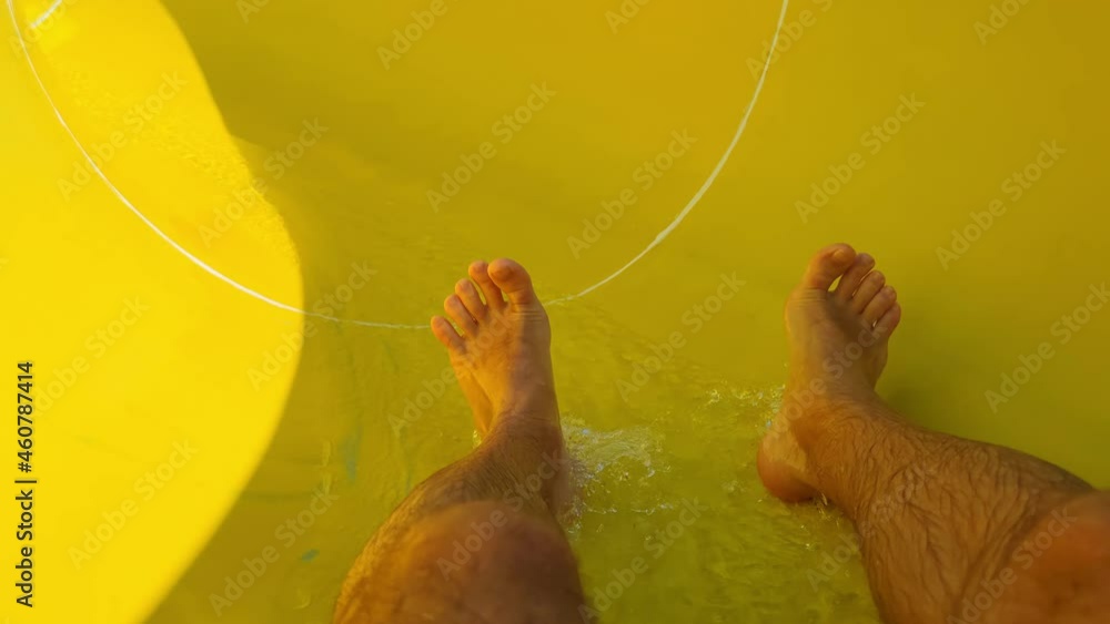 enjoying on waterslide during summer vacation, feet of man slides down ...