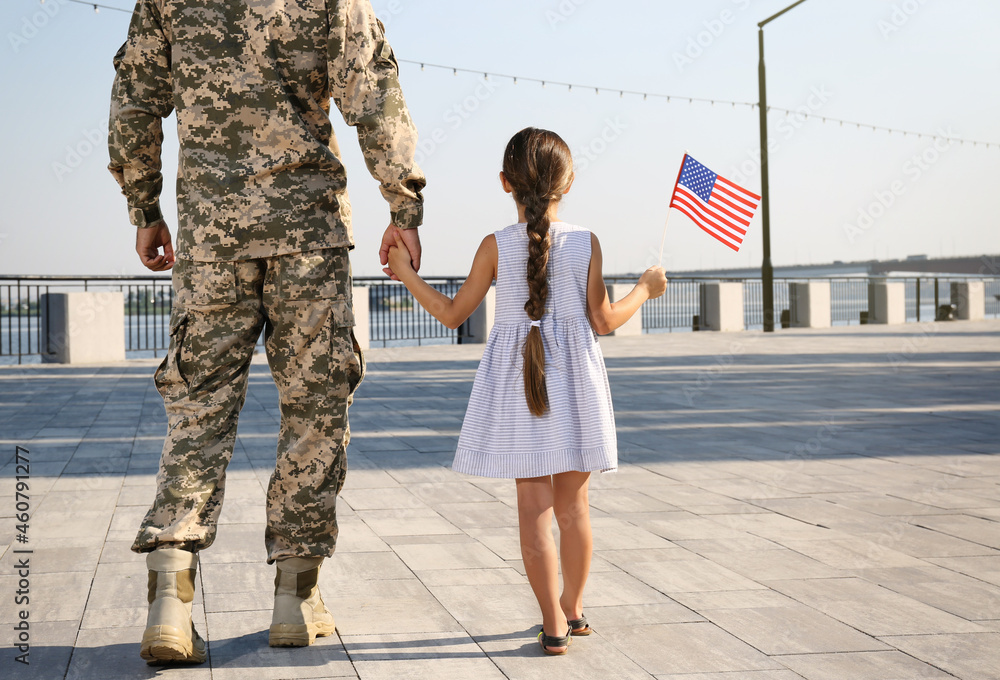Soldier and his little daughter with American flag outdoors, back view ...