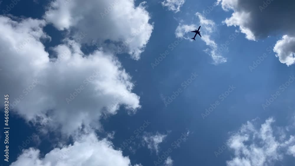 plane is flying in beautiful blue sky with white fluffy clouds. Cumulus ...