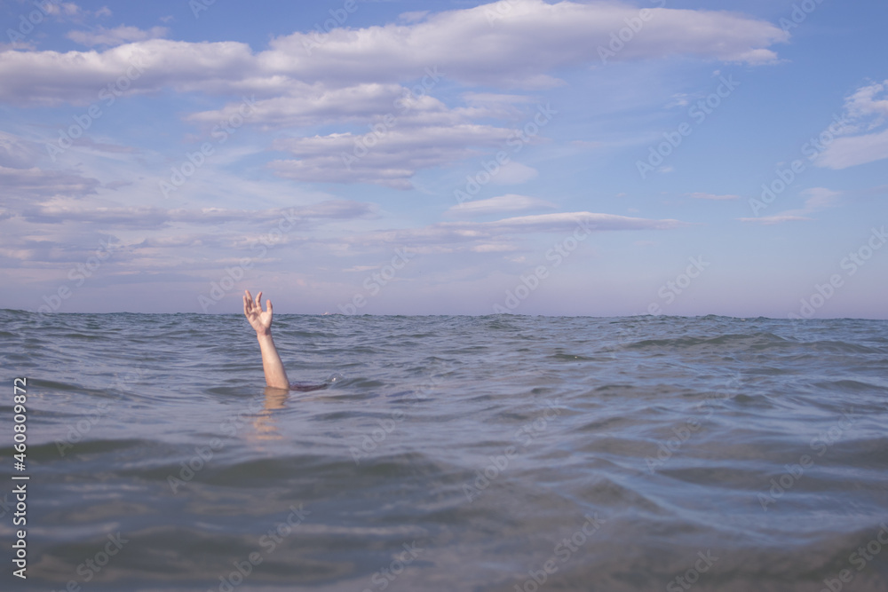 Person submerged on a beach with hand out pretending to be drowning ...