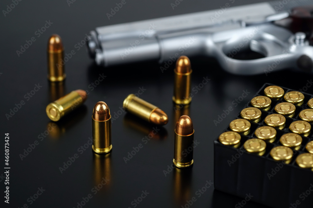 Close-Up handgun with golden sharp bullets on a black surface. Stock ...