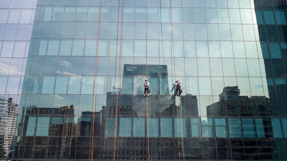 Two male workers with safety equipment at heights. Cleaning up a tall ...