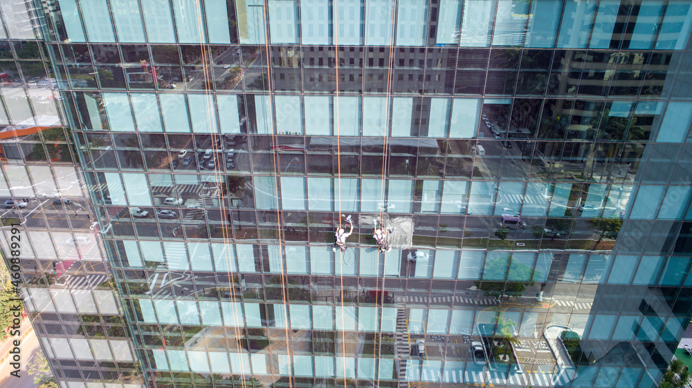 Two male workers with safety equipment at heights. Cleaning up a tall ...