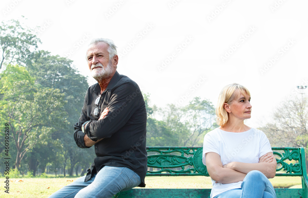 Offended mature man and woman sitting on different sides of bench ...