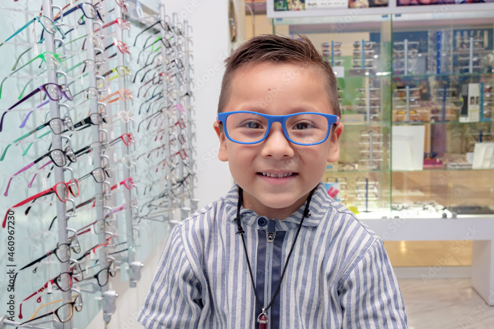 Latino boy tries on glasses and looks at the camera simulating a mirror ...
