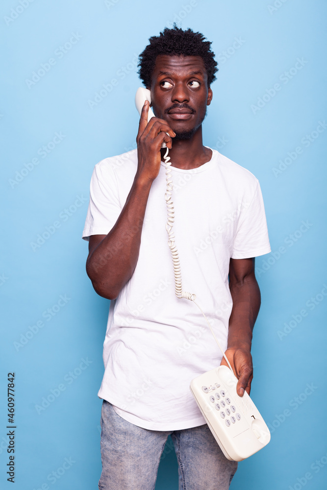 Young adult answering vintage telephone with wire. Man holding retro ...