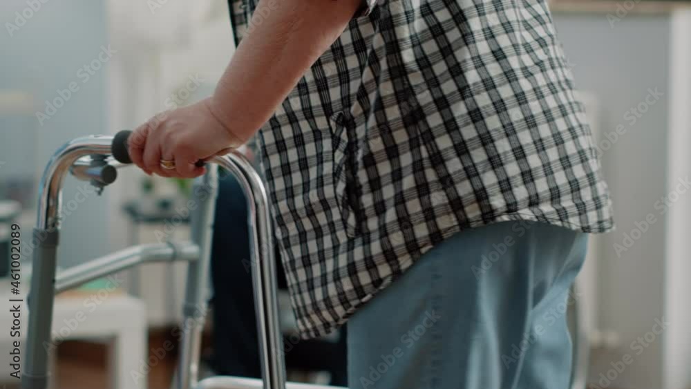 Close up of senior patient with disability using walk frame for ...