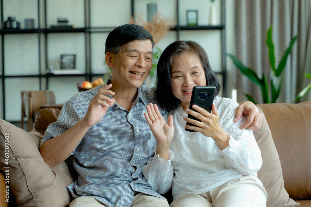 Happy elderly Asian couple doing facetime video calling with a ...