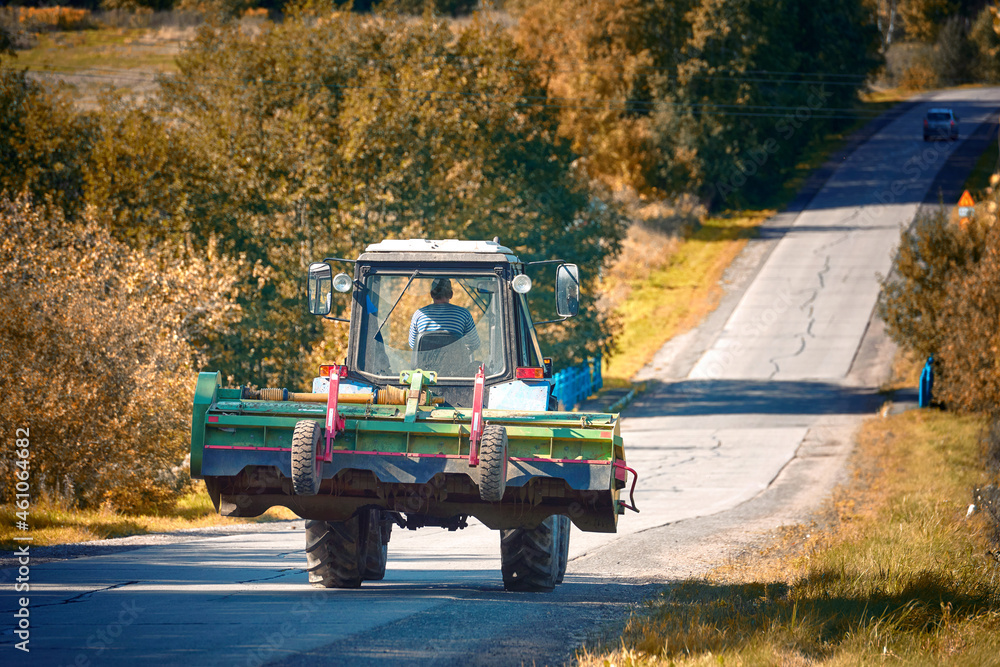 Tractor with plow driving on hilly road at countryside, agricultural ...