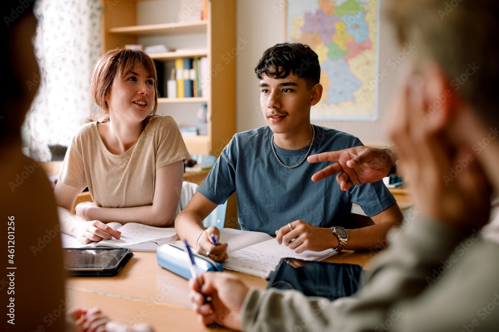 Male and female students studying together in high school classroom ...