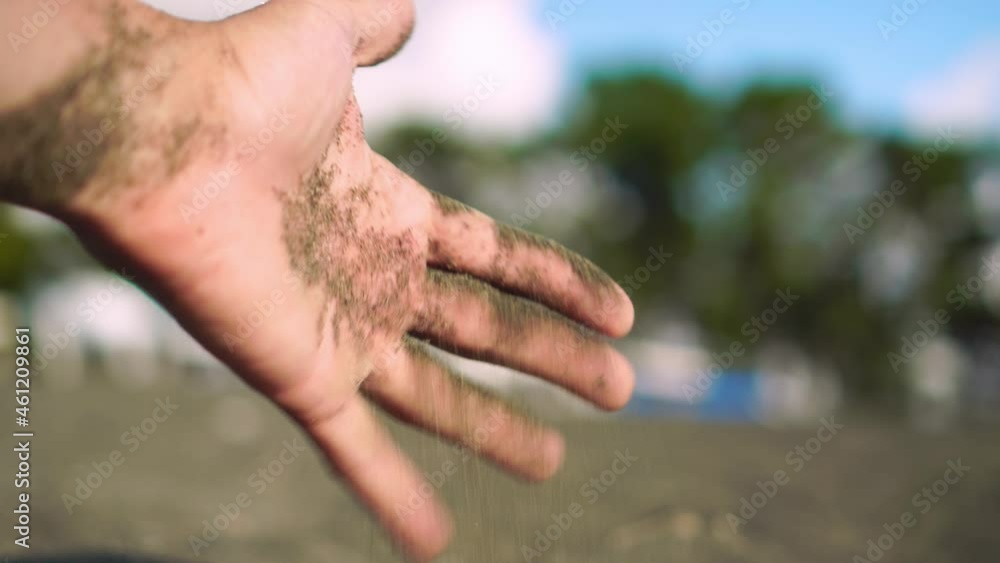 close-up of an unrecognizable hand grabs a handful of dry sand and lets ...