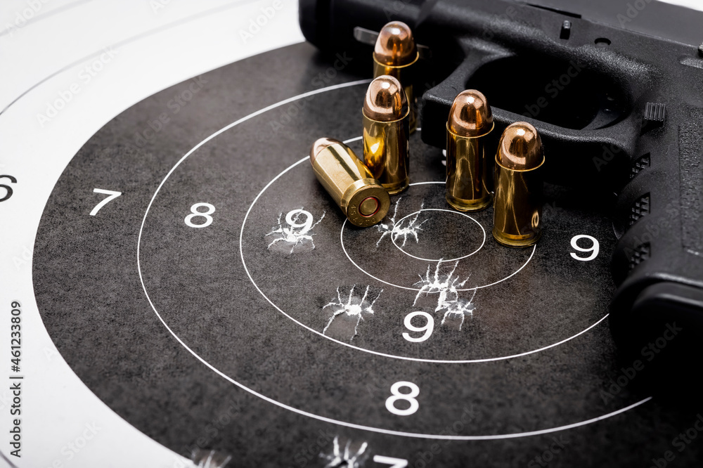 Gun bullets on bull eye paper target and semi automatic handgun ...