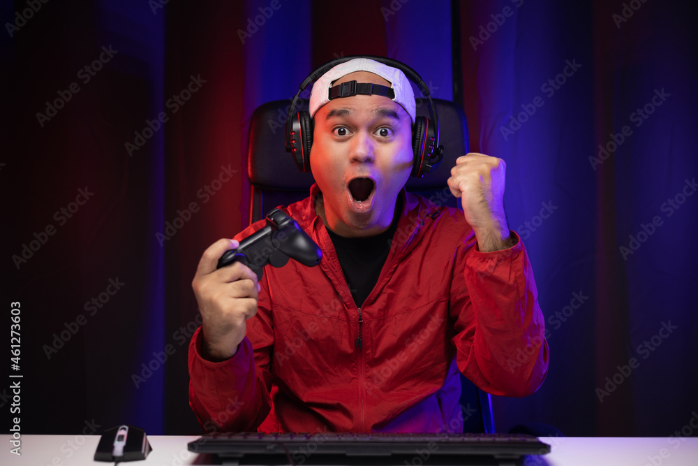 Foto de Excited and shocked face of Asian gamer with headphone holding ...