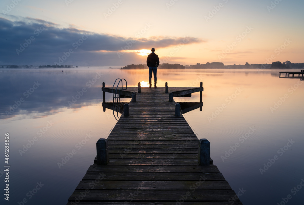 A man looking over a lake during a foggy, tranquil morning. Stock Photo ...
