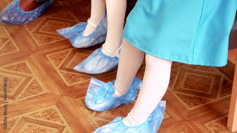 Children's feet in blue medical shoe covers on the floor. Protecting ...