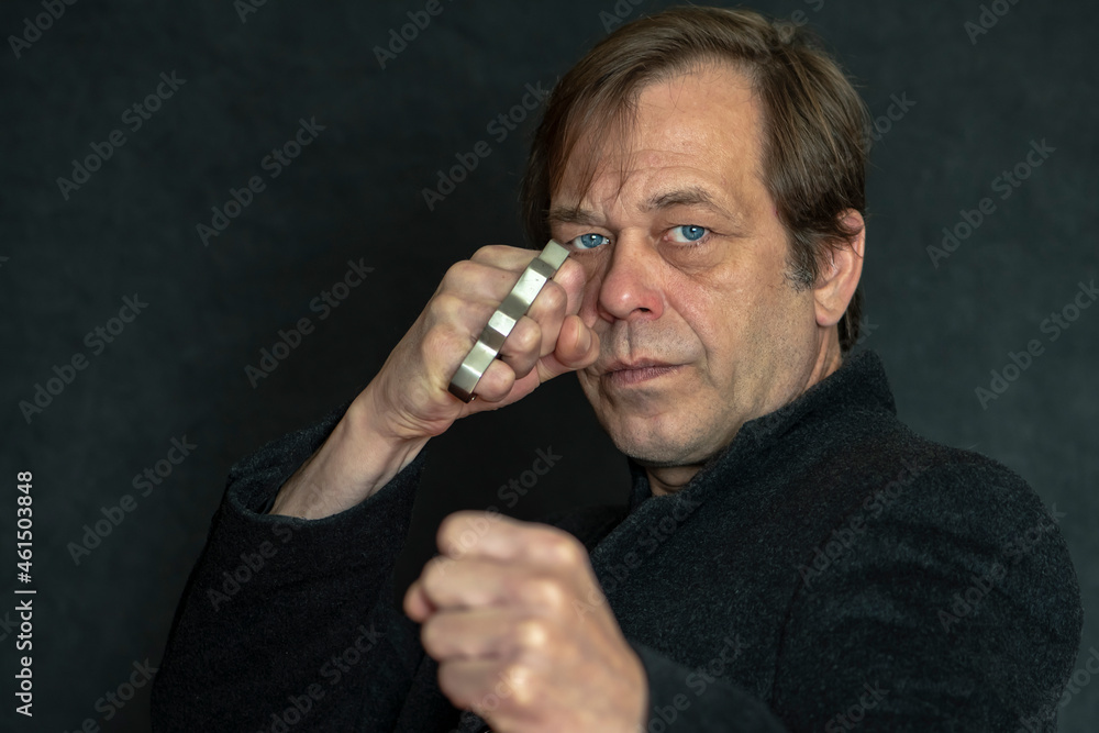 Portrait of a 45-50-year-old man with brass knuckles in his hand in a ...