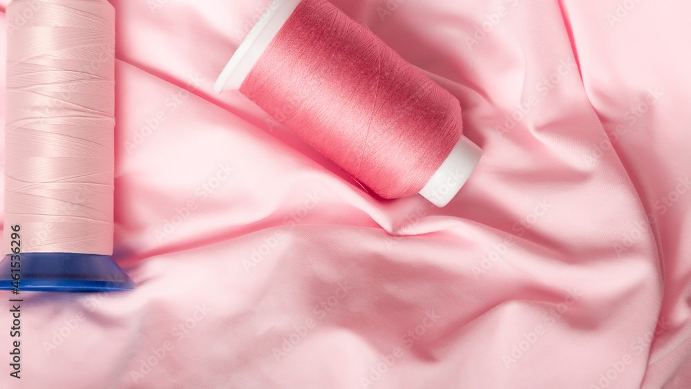 Tailoring accessories. Pink thread spools with fabric. background ...